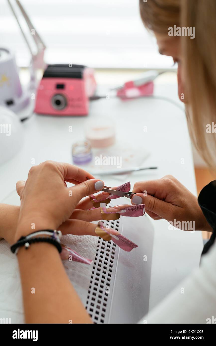 Side view of crop concentrated young female manicurist cutting tips ...