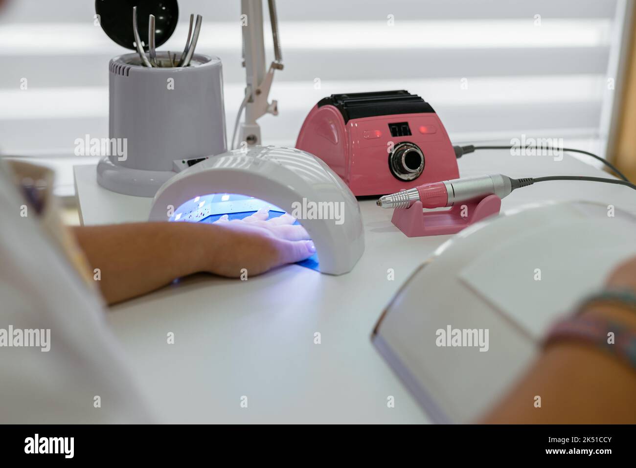 High angle of crop anonymous female client putting hand into nail UV ...