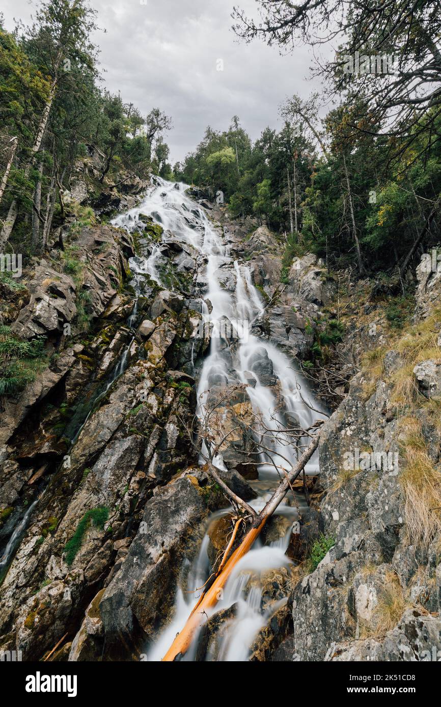 Low angle of fast flowing waterfall in rocky terrain in woods located ...