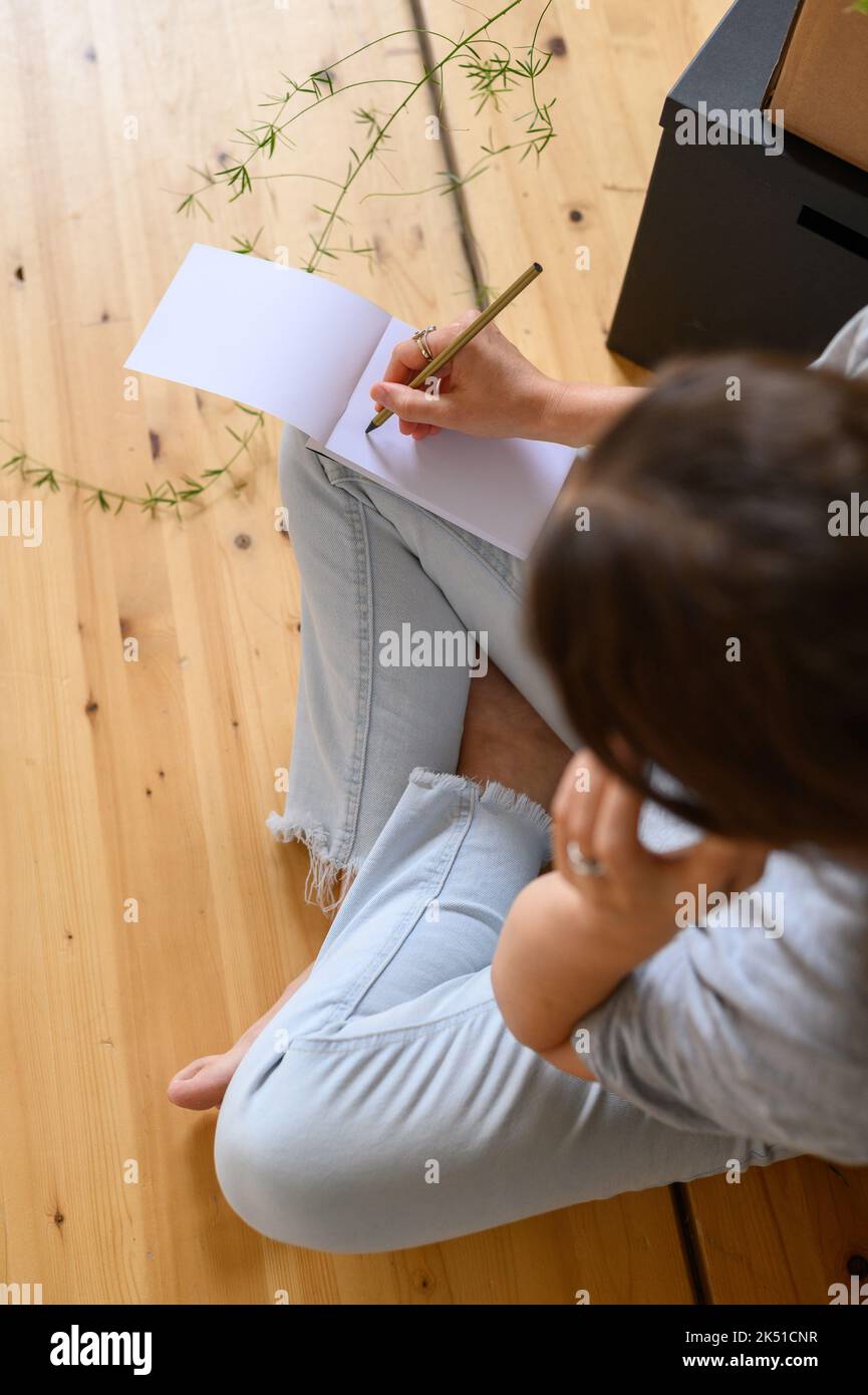 Top view of unrecognizable female in casual clothes writing down data ...