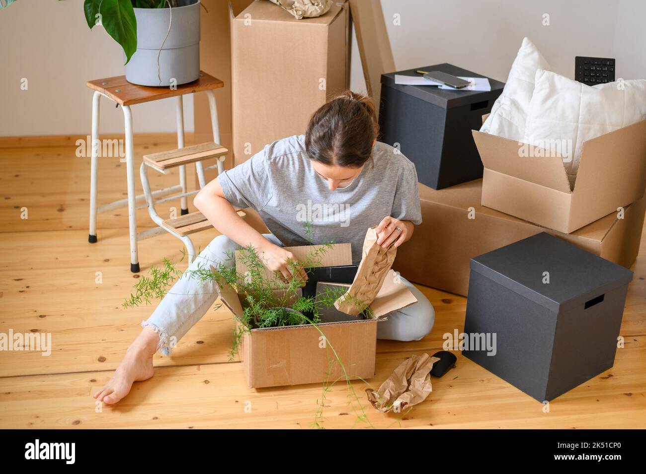 From above barefoot woman in casual clothes removing paper from carton ...