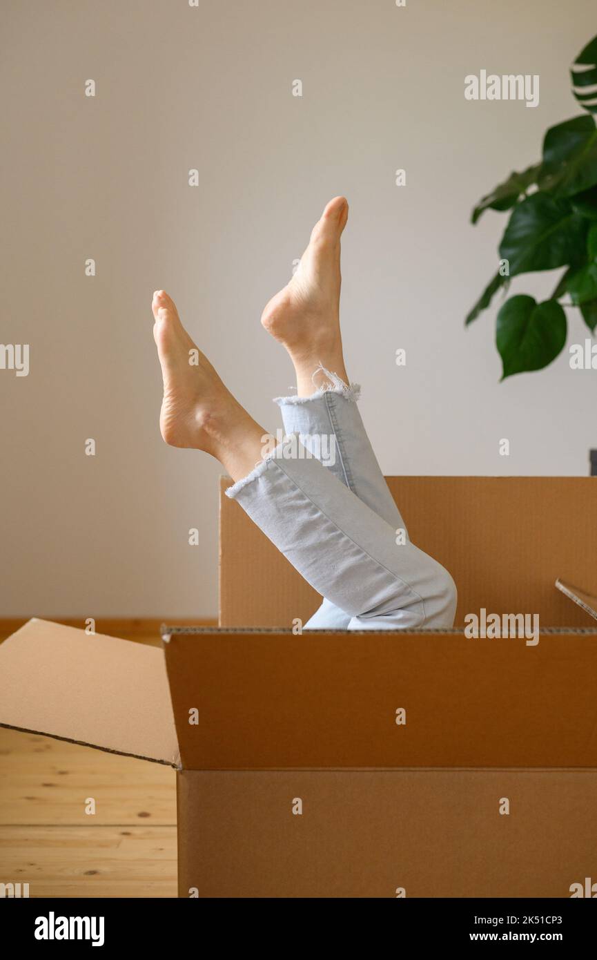 Unrecognizable barefoot female in jeans raising legs and arms while ...