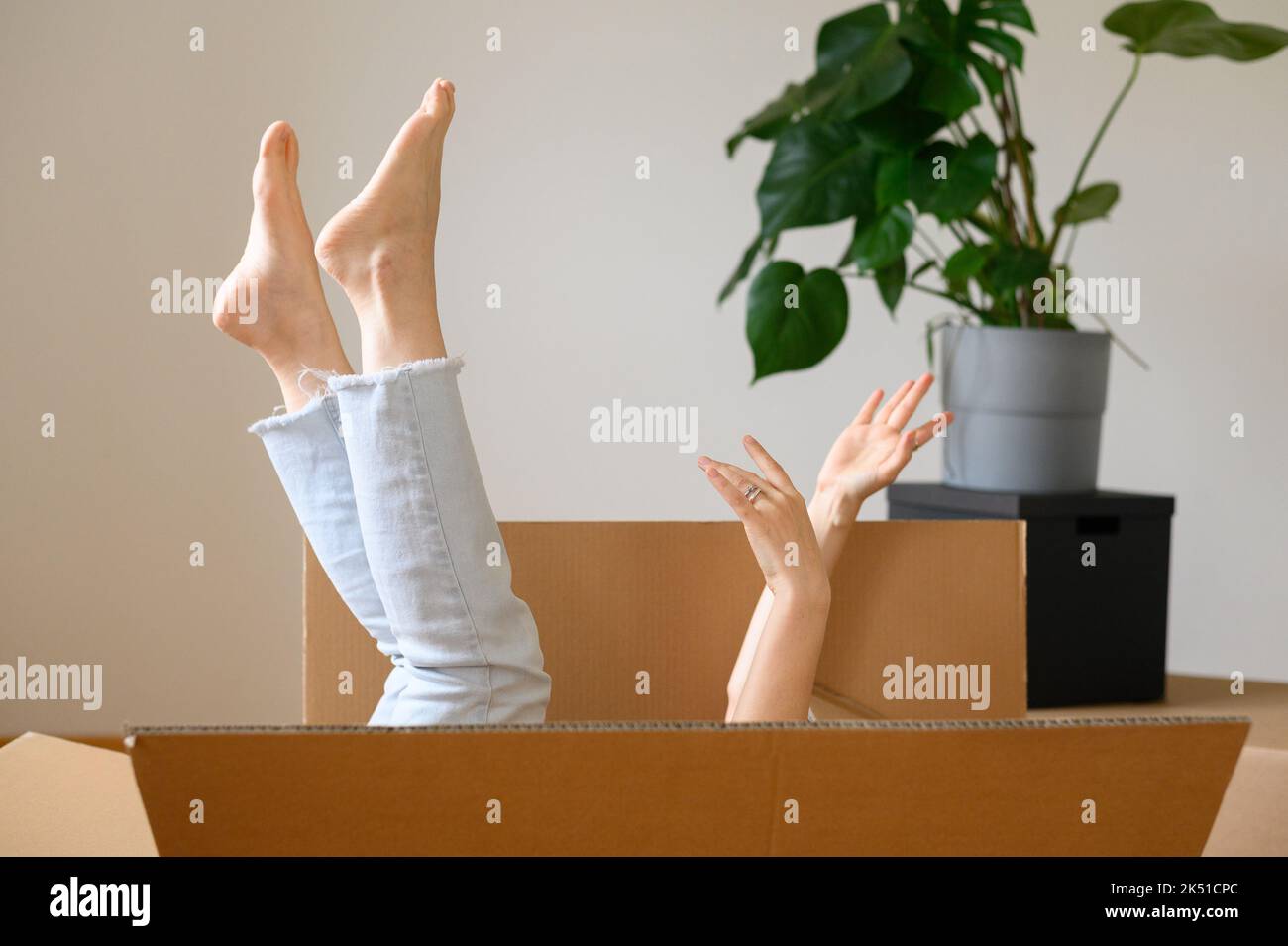 Unrecognizable barefoot female in jeans raising legs while lying inside ...