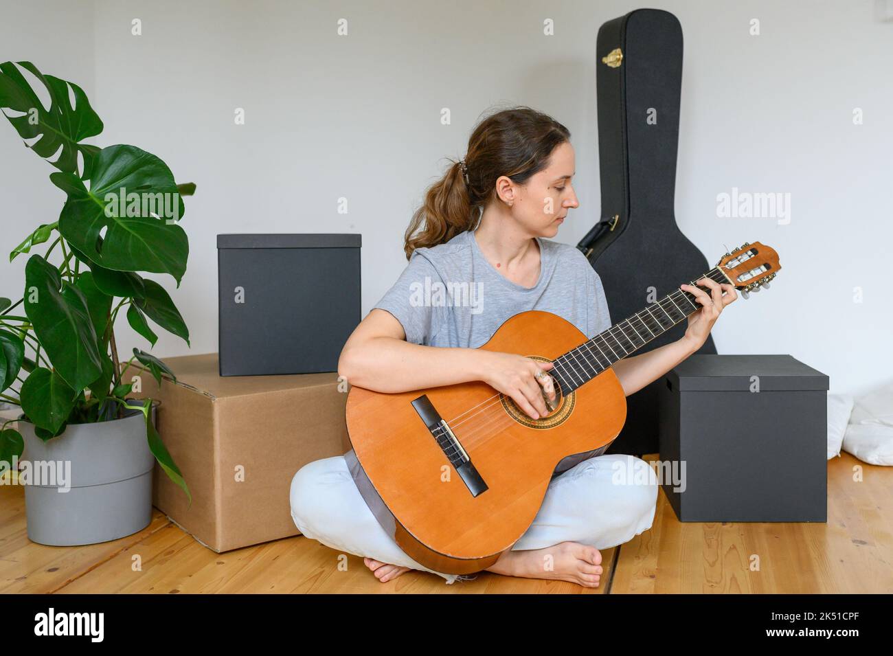 Merry young female musician smiling and playing guitar while sitting ...