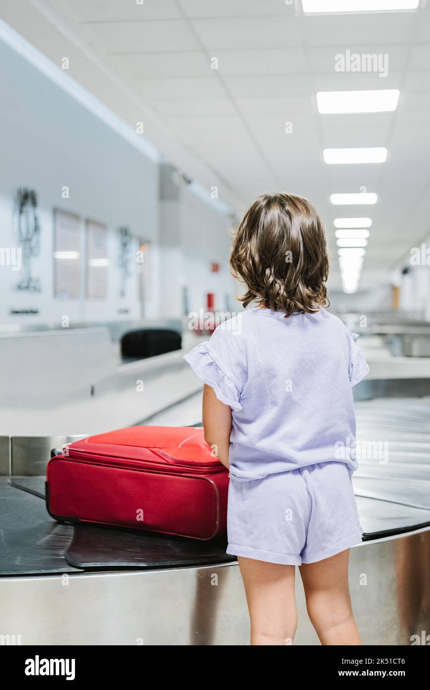 Back view of unrecognizable girl in lilac clothes waiting for luggage ...