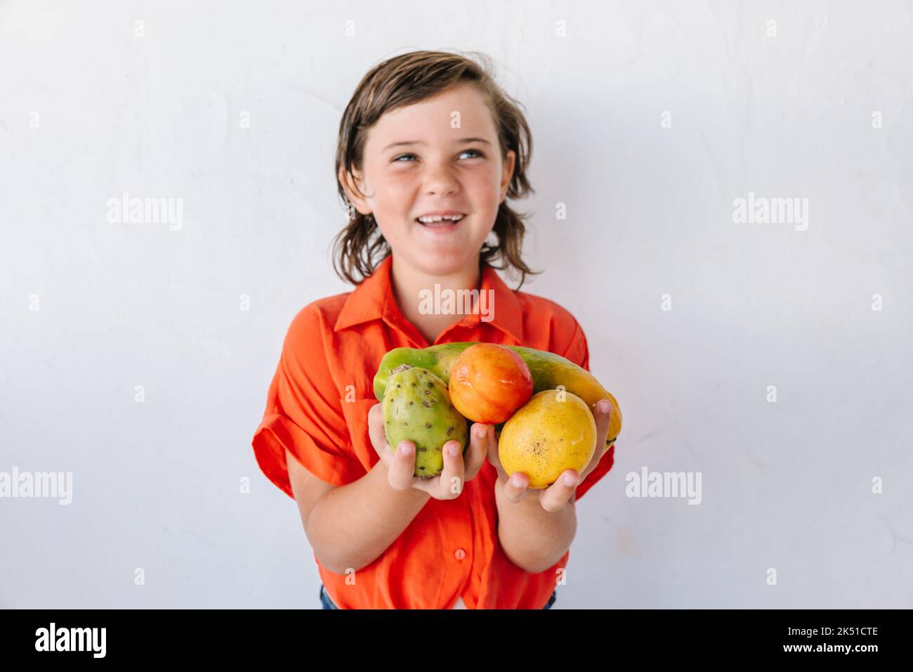 Adorable little girl in bright red shirt happily looking away while ...