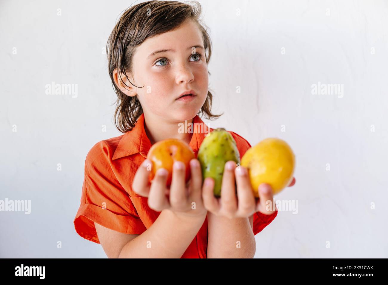 Adorable little girl in bright red shirt looking away while ...