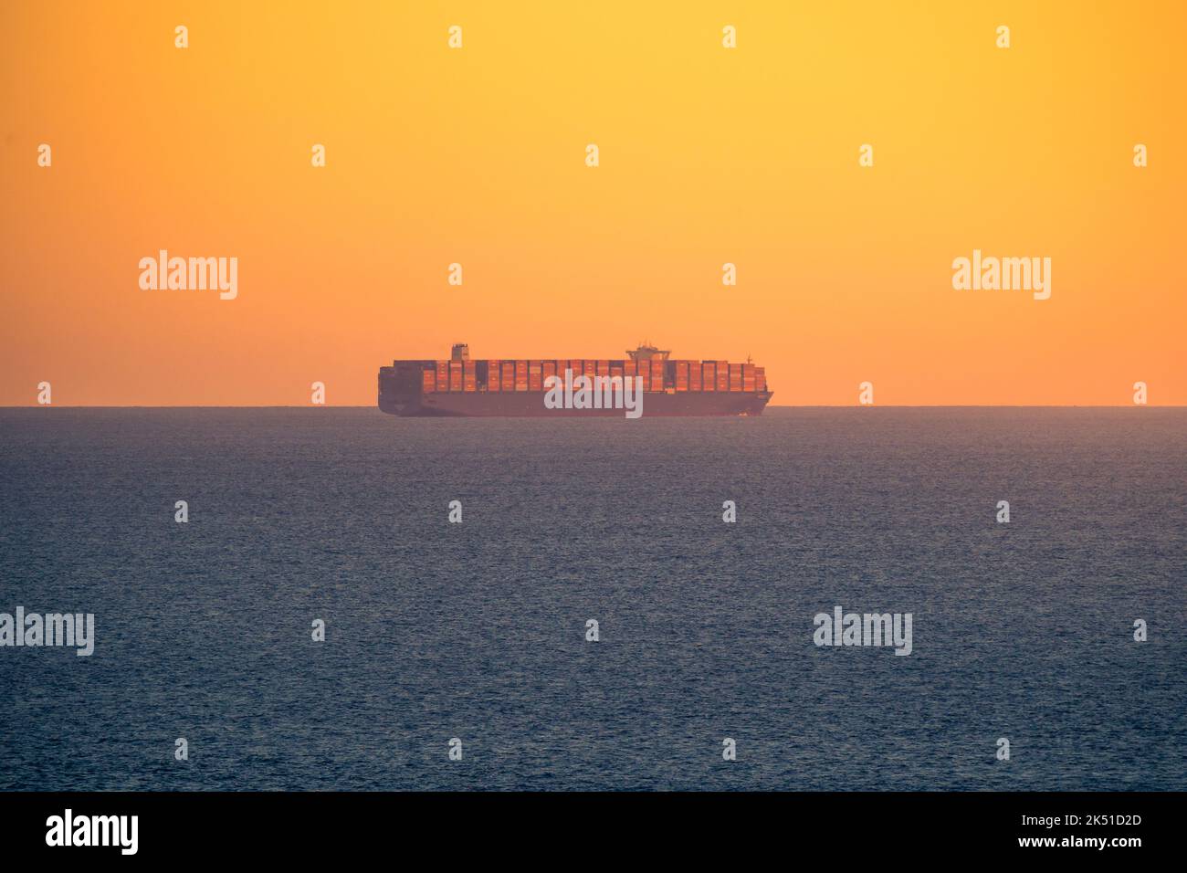 Distant barge with cargo containers sailing in dark rippling water of ...