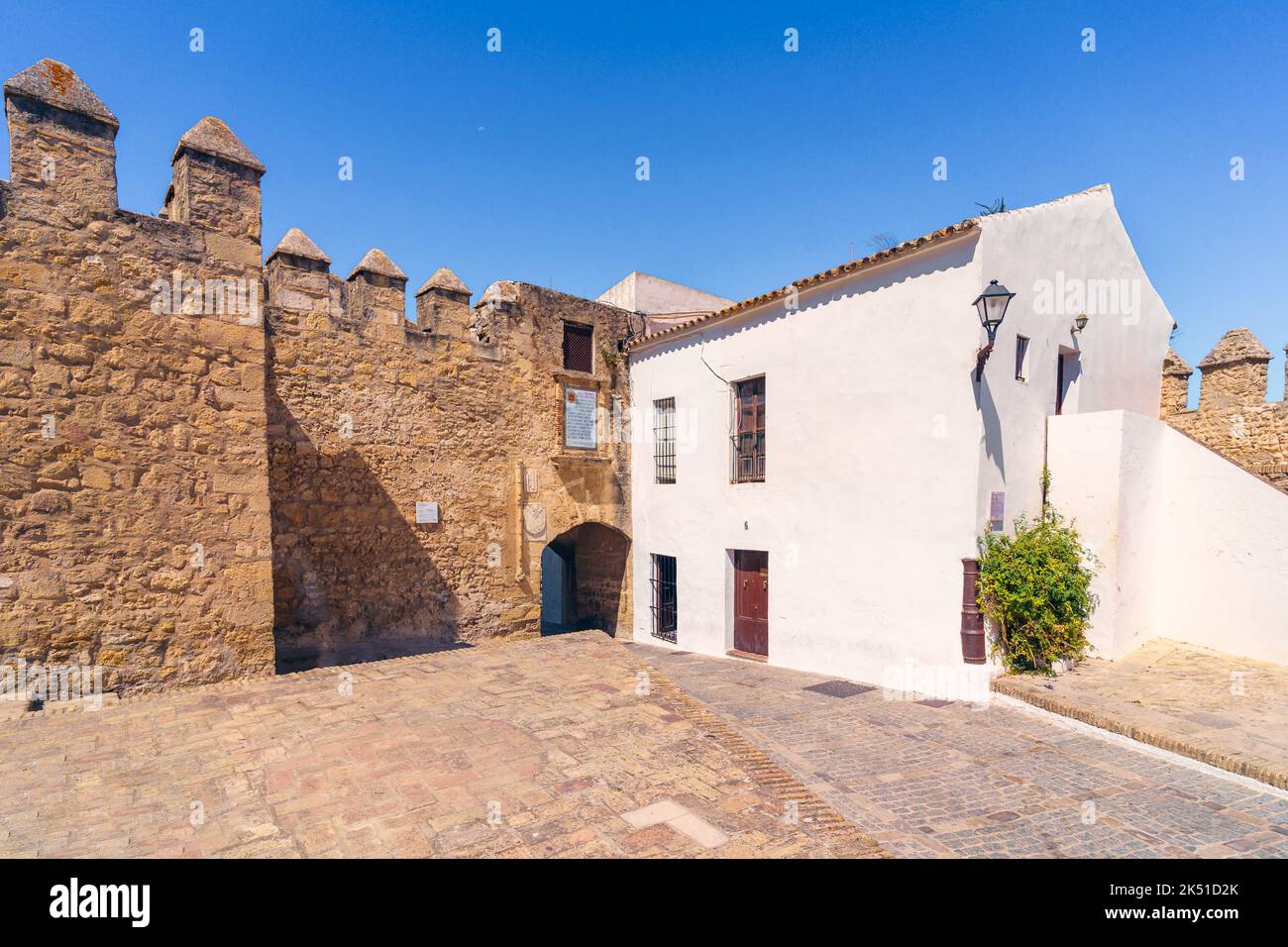 Exterior of white plaster low rise house with stone wall and paved yard ...