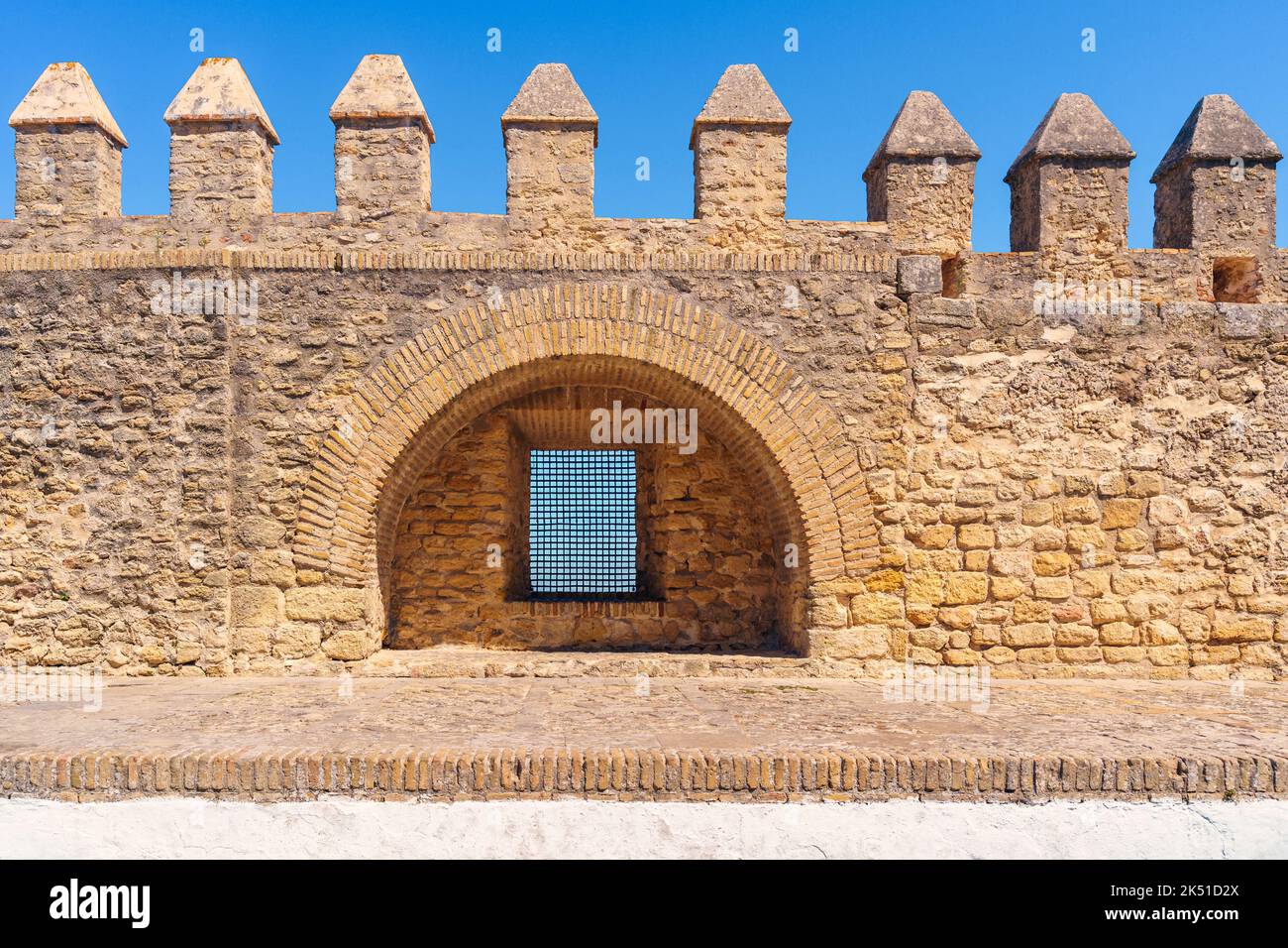 Facade of old brick wall of town fort with latticed window in arch and ...