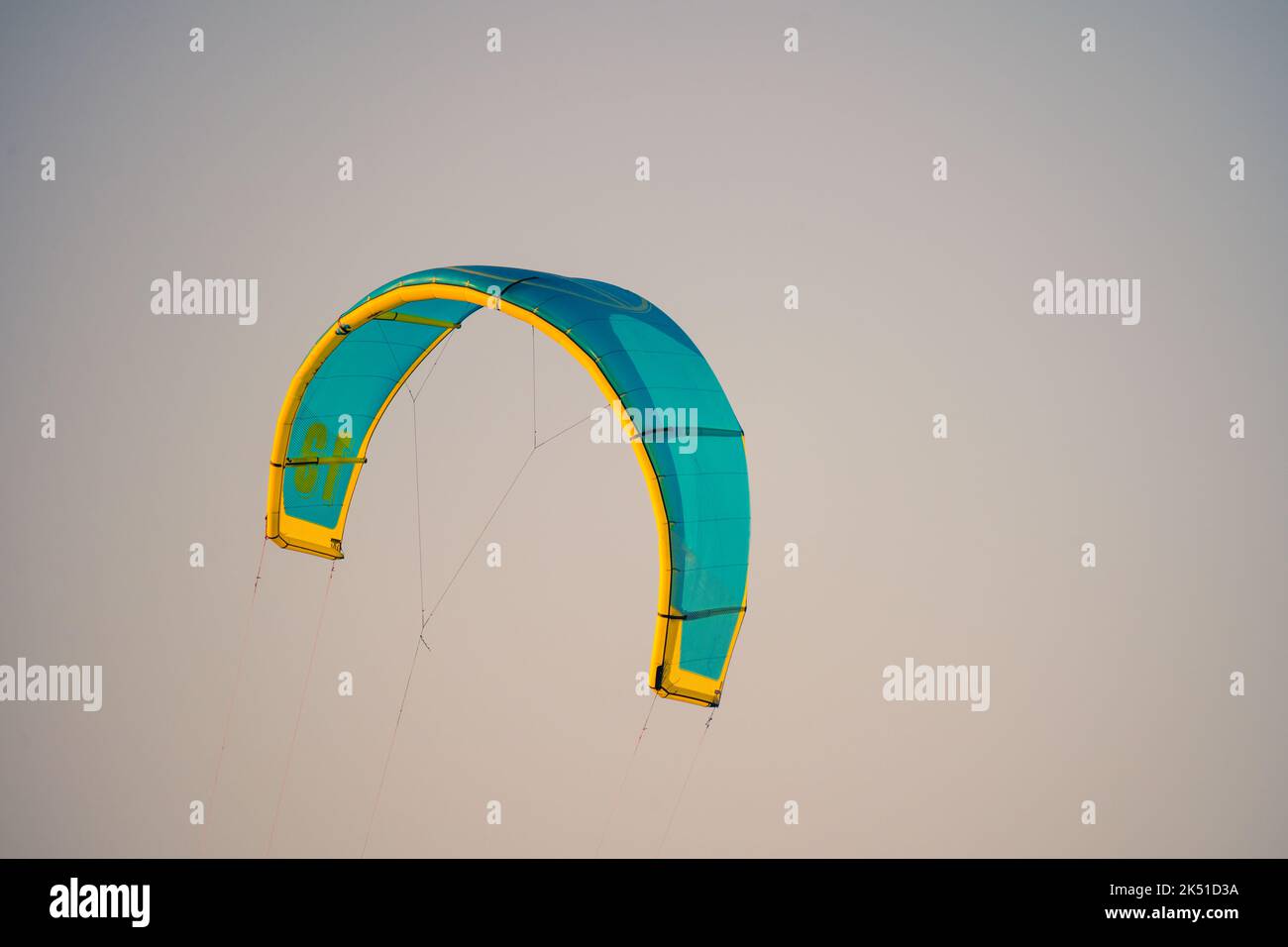 Multicolored yellow and blue parachute of parasailer flying high in air ...