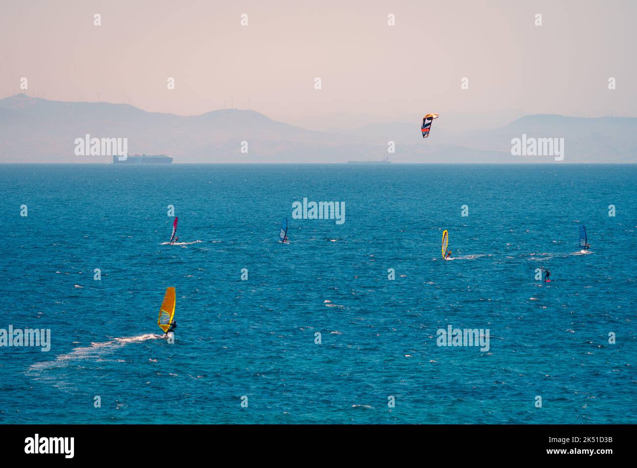 High angle of people windsurfing and parasailing on rippling turquoise ...