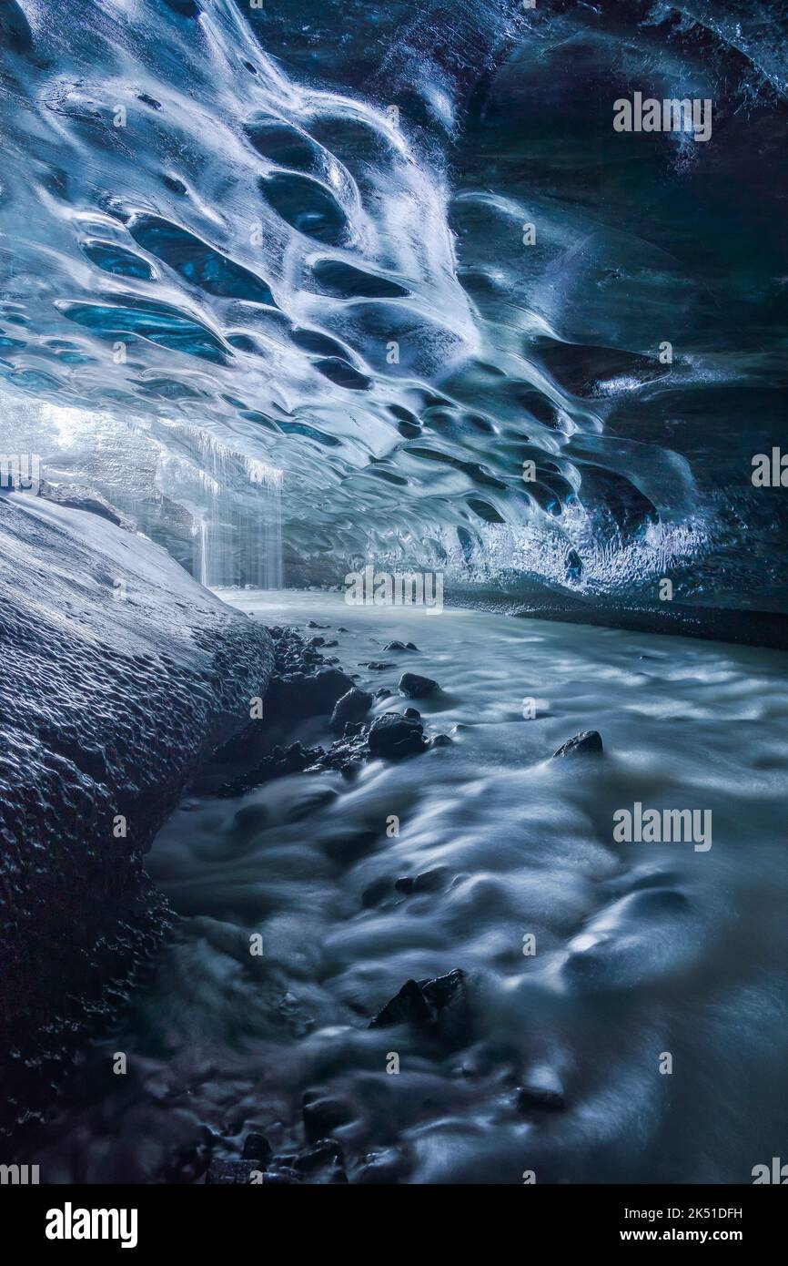 Trickles of clean water falling from blue ceiling of ice cave on rocky ...