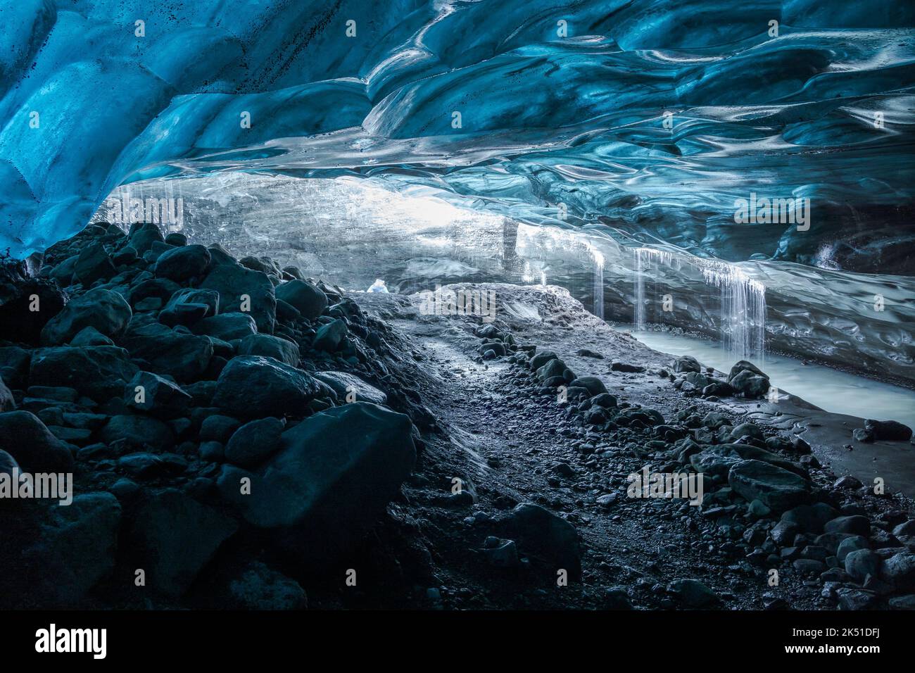 Trickles of clean water falling from blue ceiling of ice cave on rocky ...