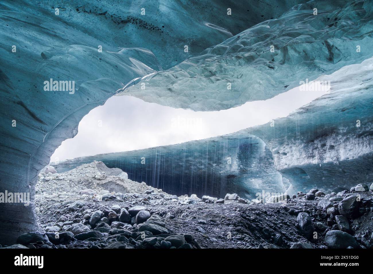 Clean water falling from fragile transparent icicles into blue stream ...