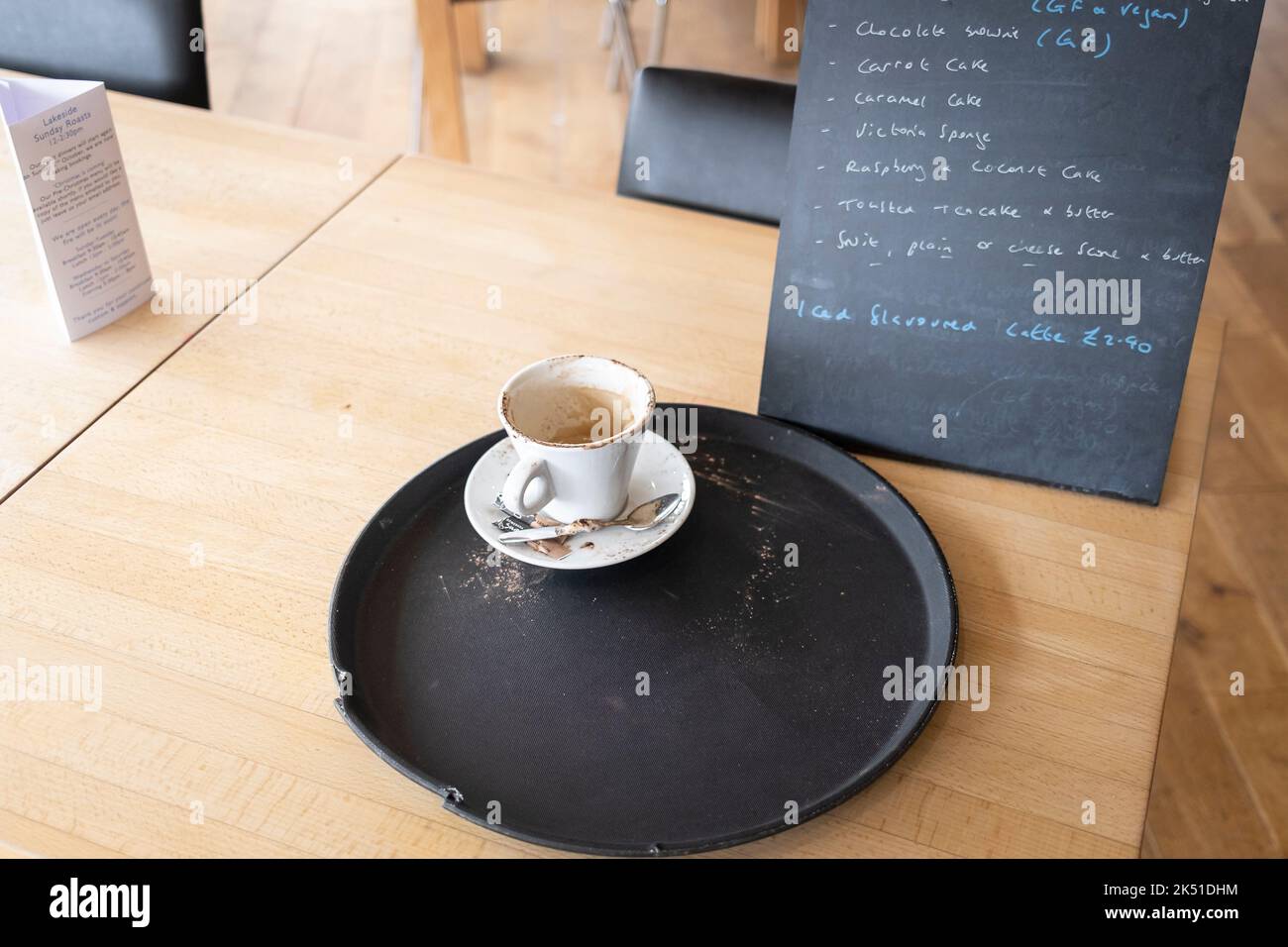 An empty used cappucino coffee cup on a tray next to a hand written ...