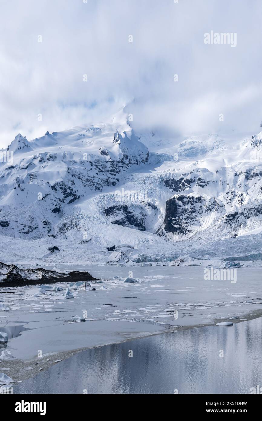 Breathtaking scenery of rocky mountains covered with snow near frozen ...