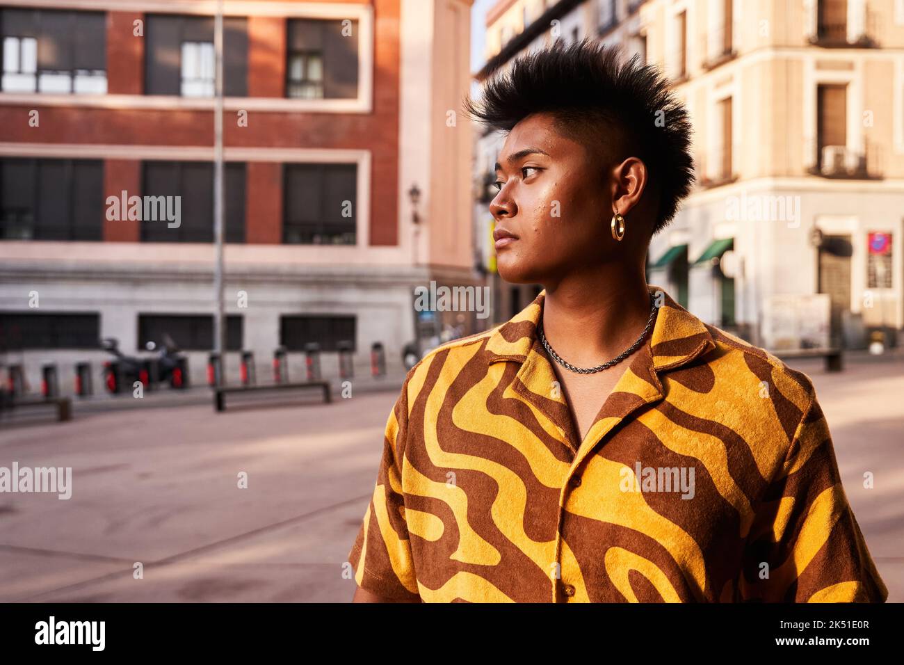 Serious Asian transgender woman with short hair looking away while ...