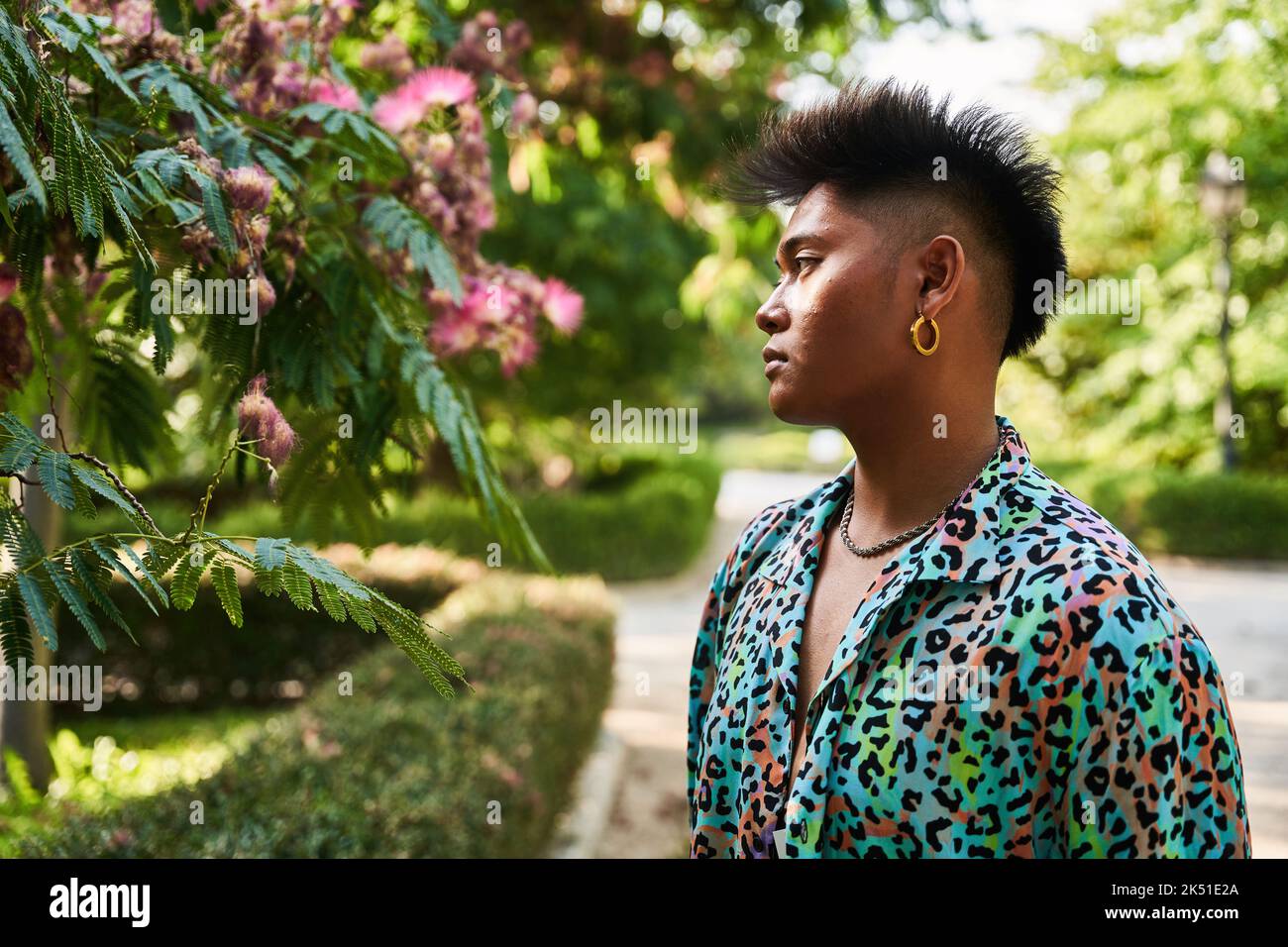Thoughtful Asian non binary person without makeup looking away standing ...