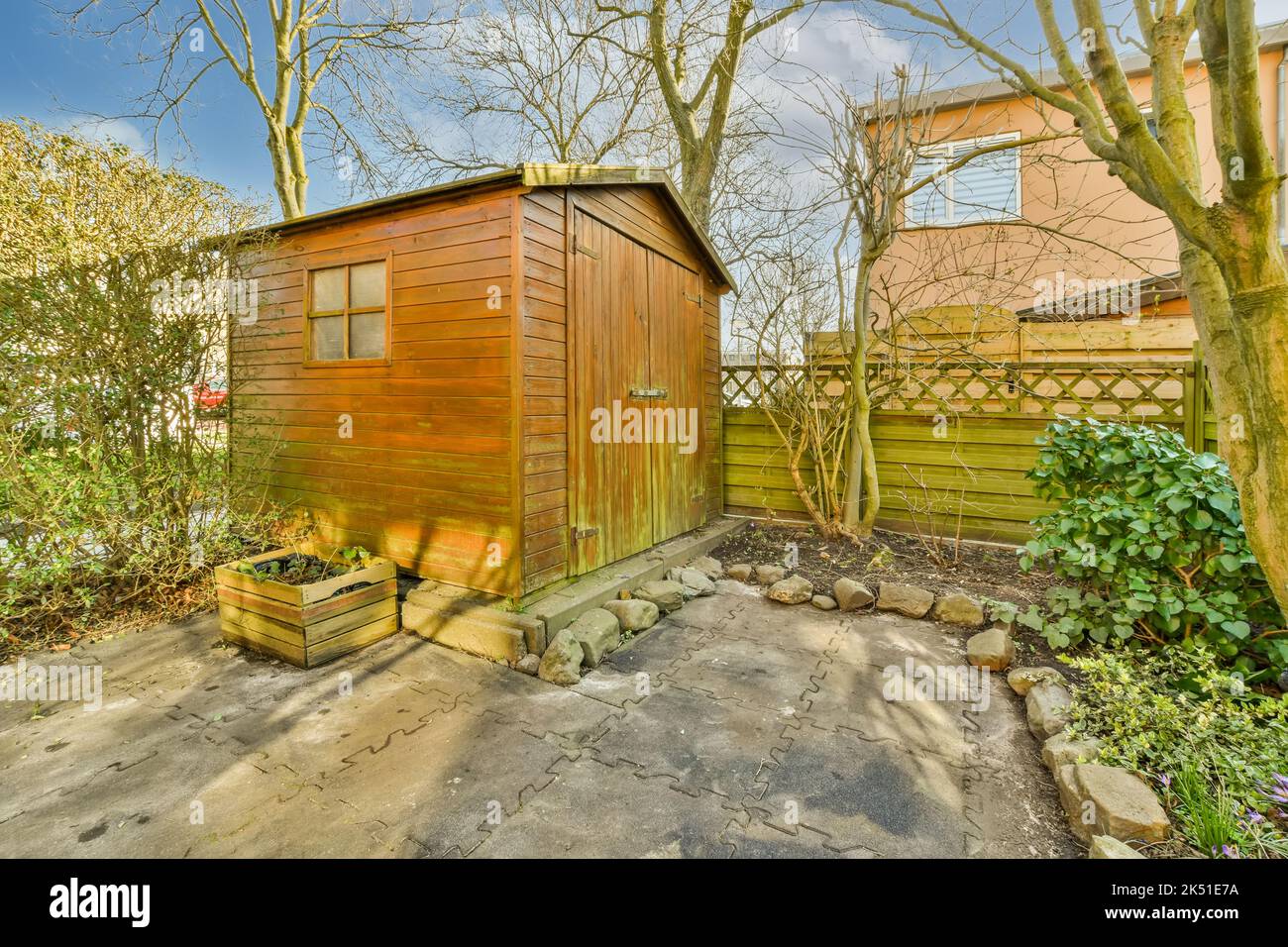 Wooden shed located on terrace of exterior house with lush green bushes ...