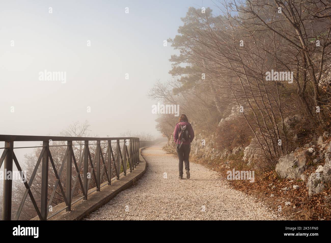 Back view of a Woman walking alone on rural misty path called Napoleonica, Trieste Stock Photo ...