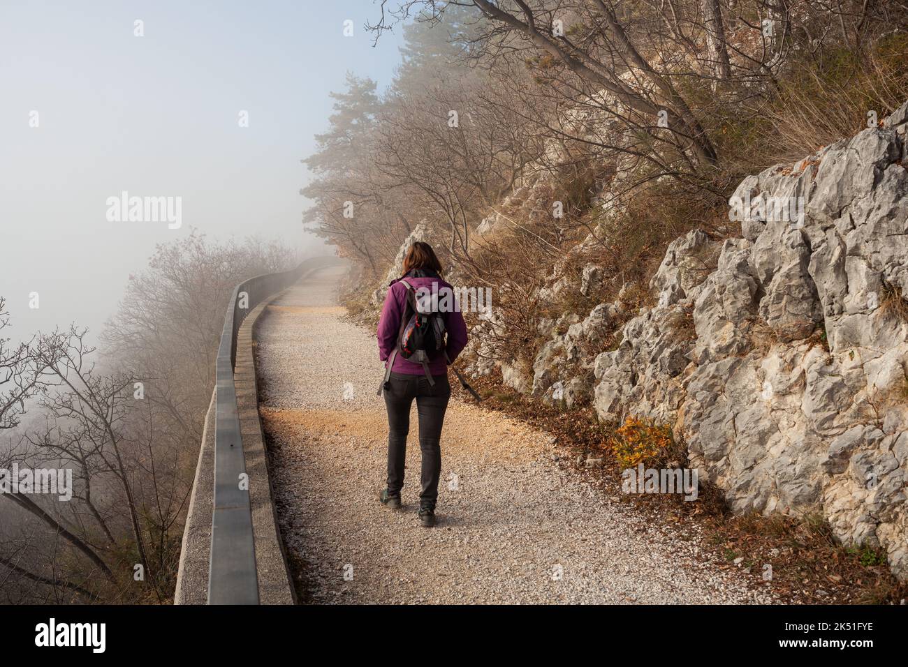 Back view of a Woman walking alone on rural misty path called ...