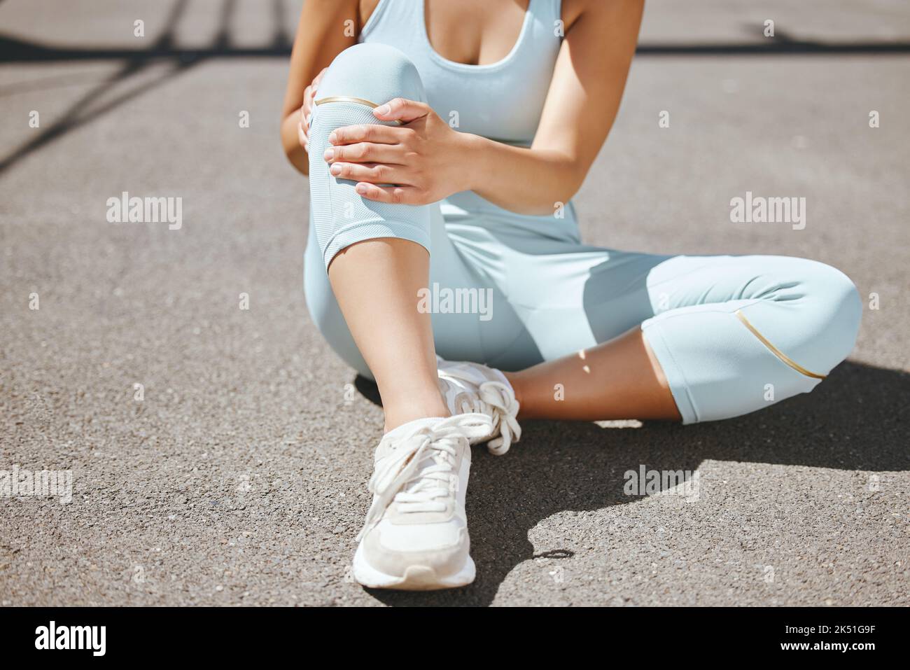 Sports injury, knee pain and fitness woman sitting on tarmac road ...