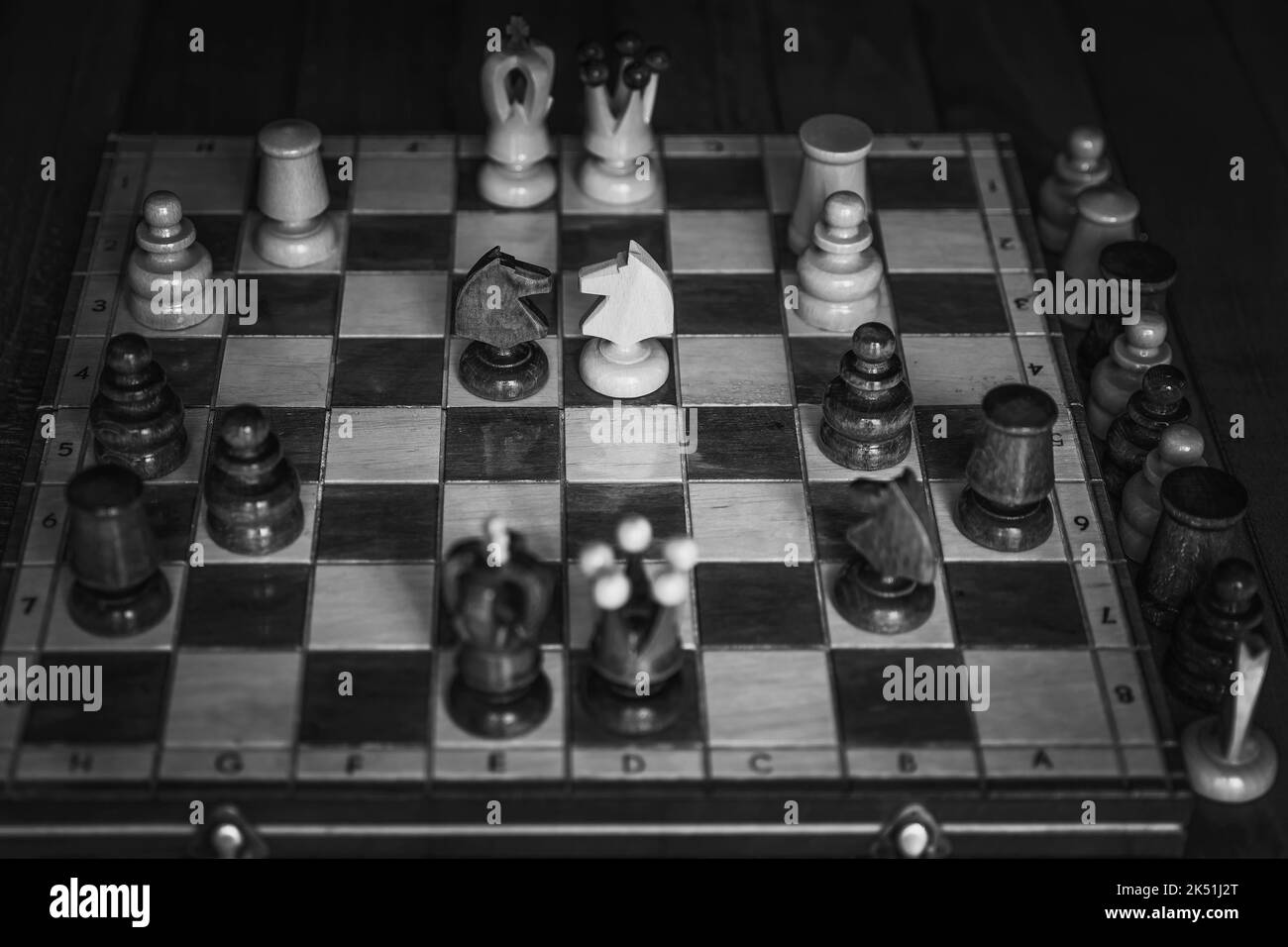Black and white overhead shot of a wooden chess board with some pieces ...