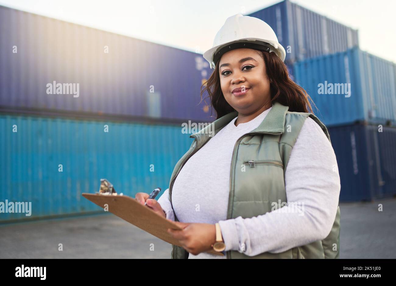 Logistics, supply chain and shipping with a delivery woman working on a dock with documents on a ...