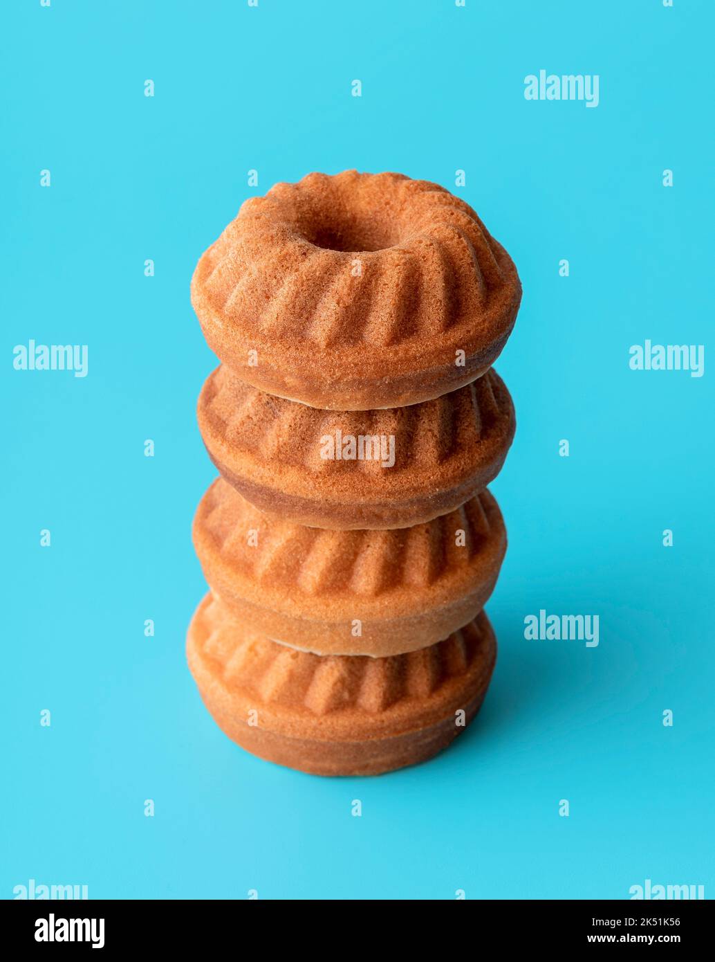 Close-up with a stack of mini bundt cakes, minimalist on a blue table ...