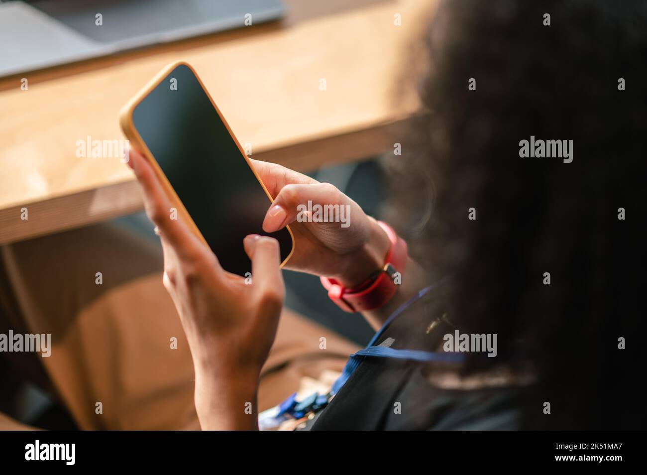 Dark-haired woman holding a smartphone in hand and typing a message ...