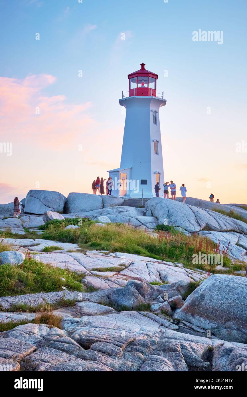 Tourists at the iconic Peggy's Cove Lighthouse at sunset Stock Photo ...