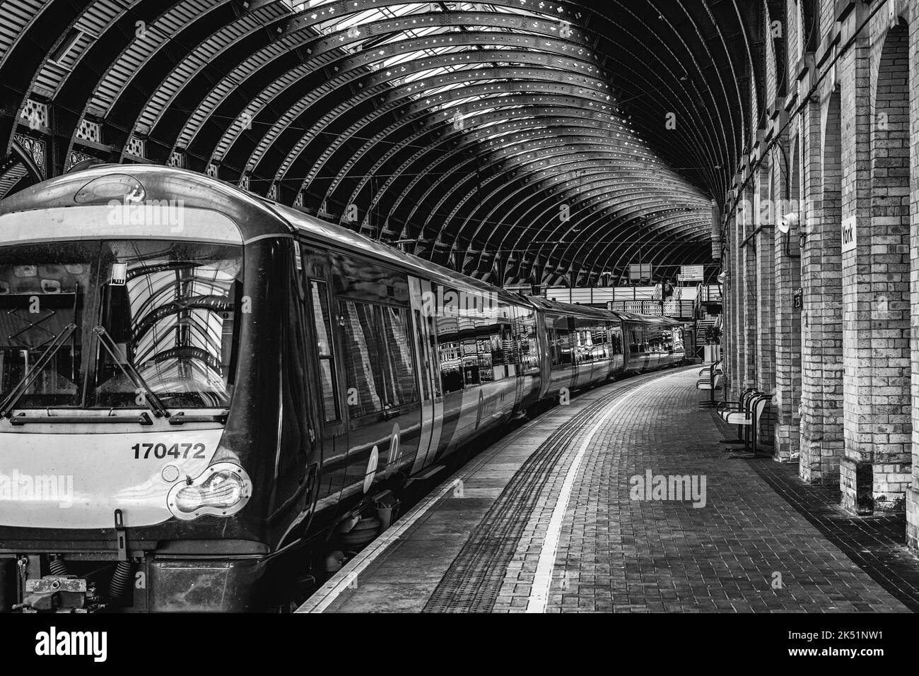 Railway carriages are resting alongside a station platform. There are ...
