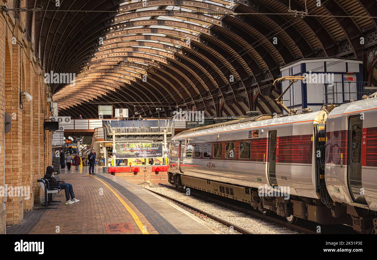 Railway carriages are resting alongside a station platform. There are ...