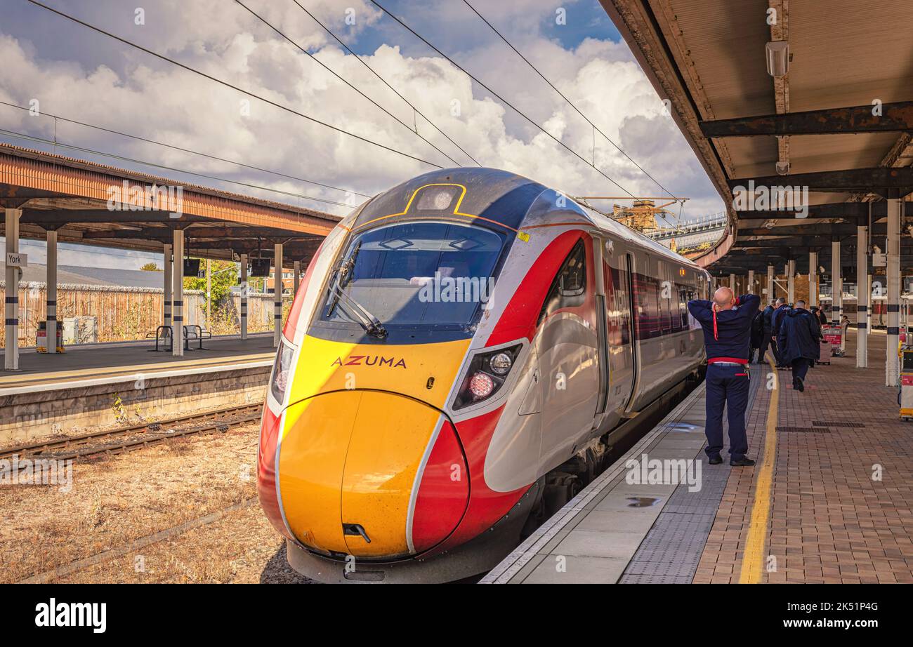 A railway train stops at station platform. A crew member stretches as ...