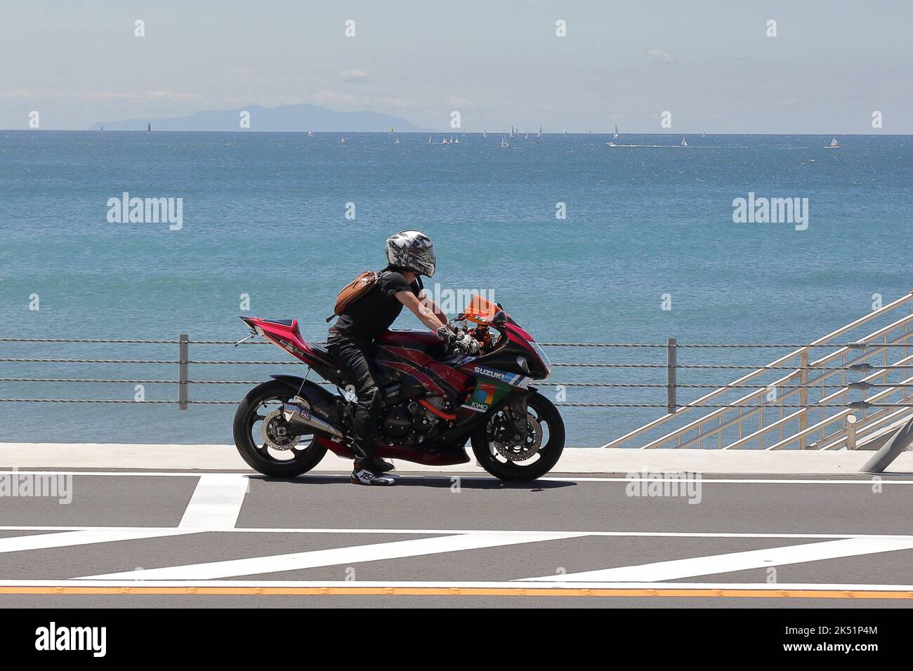 a motorcycle rider stops by the road along the Sagami Bay in the Shonan ...