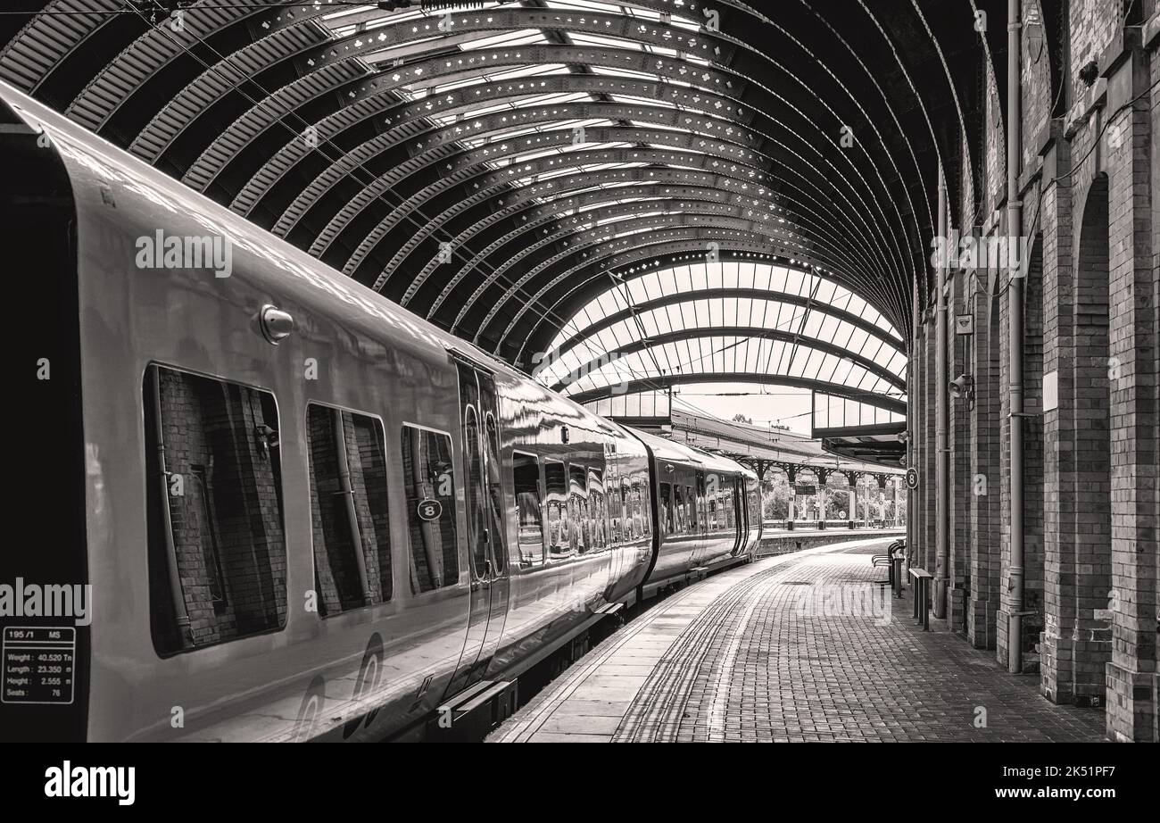 Railway carriages are resting alongside a station platform. There are ...