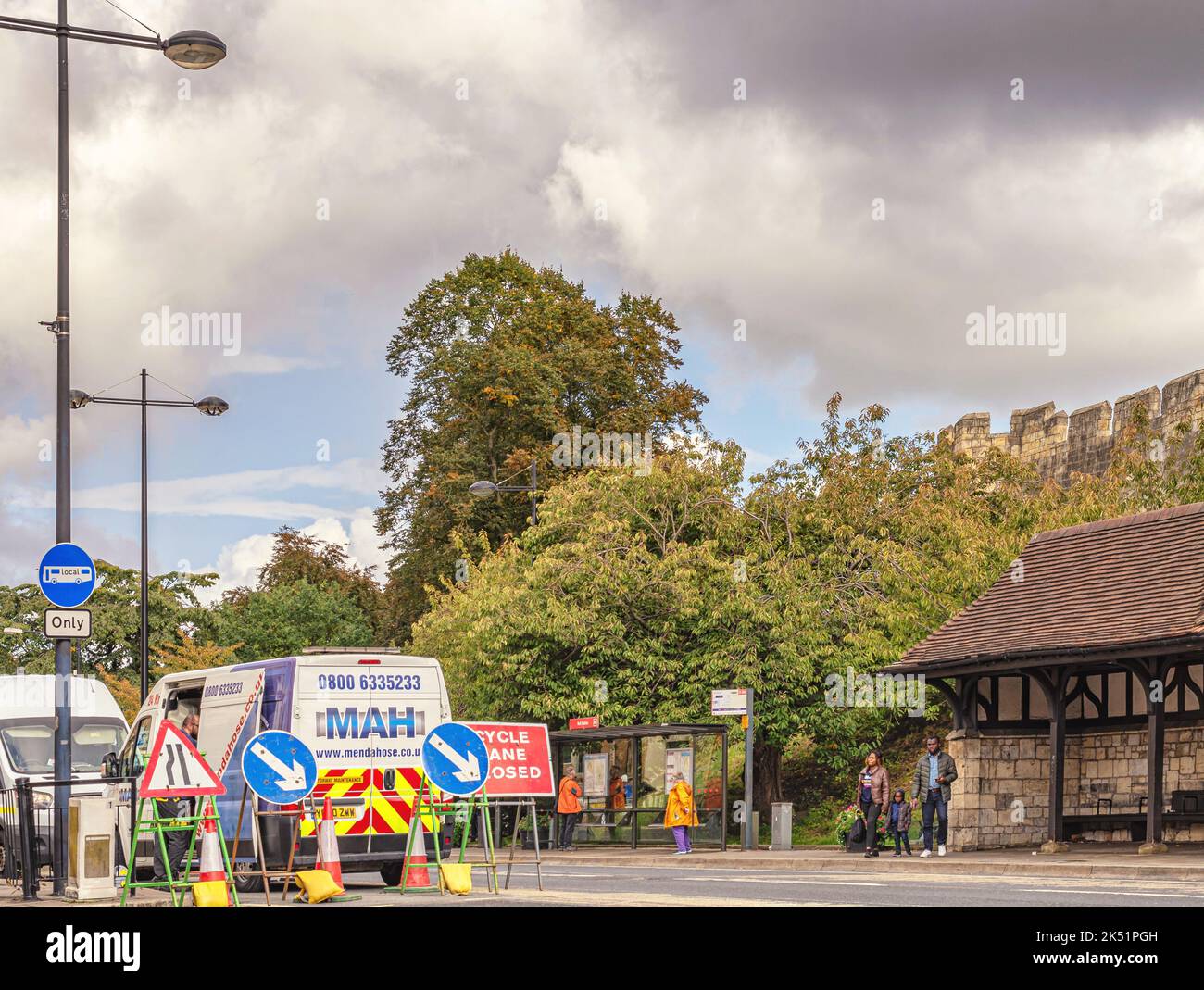 A typical scene of a roadworks with two vans parked on the road. Bus ...