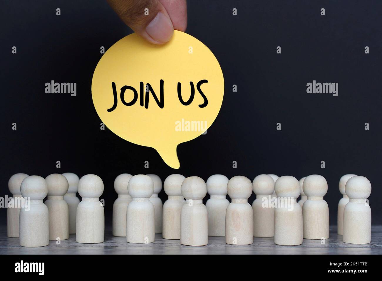 Group of wooden dolls and speech bubble with text JOIN US on black ...