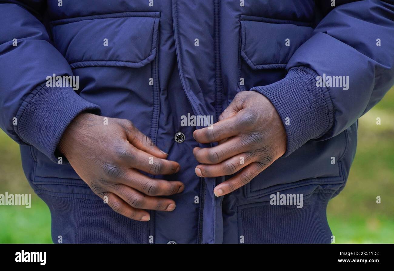 Black hands put on a blue winter coat close-up Stock Photo - Alamy