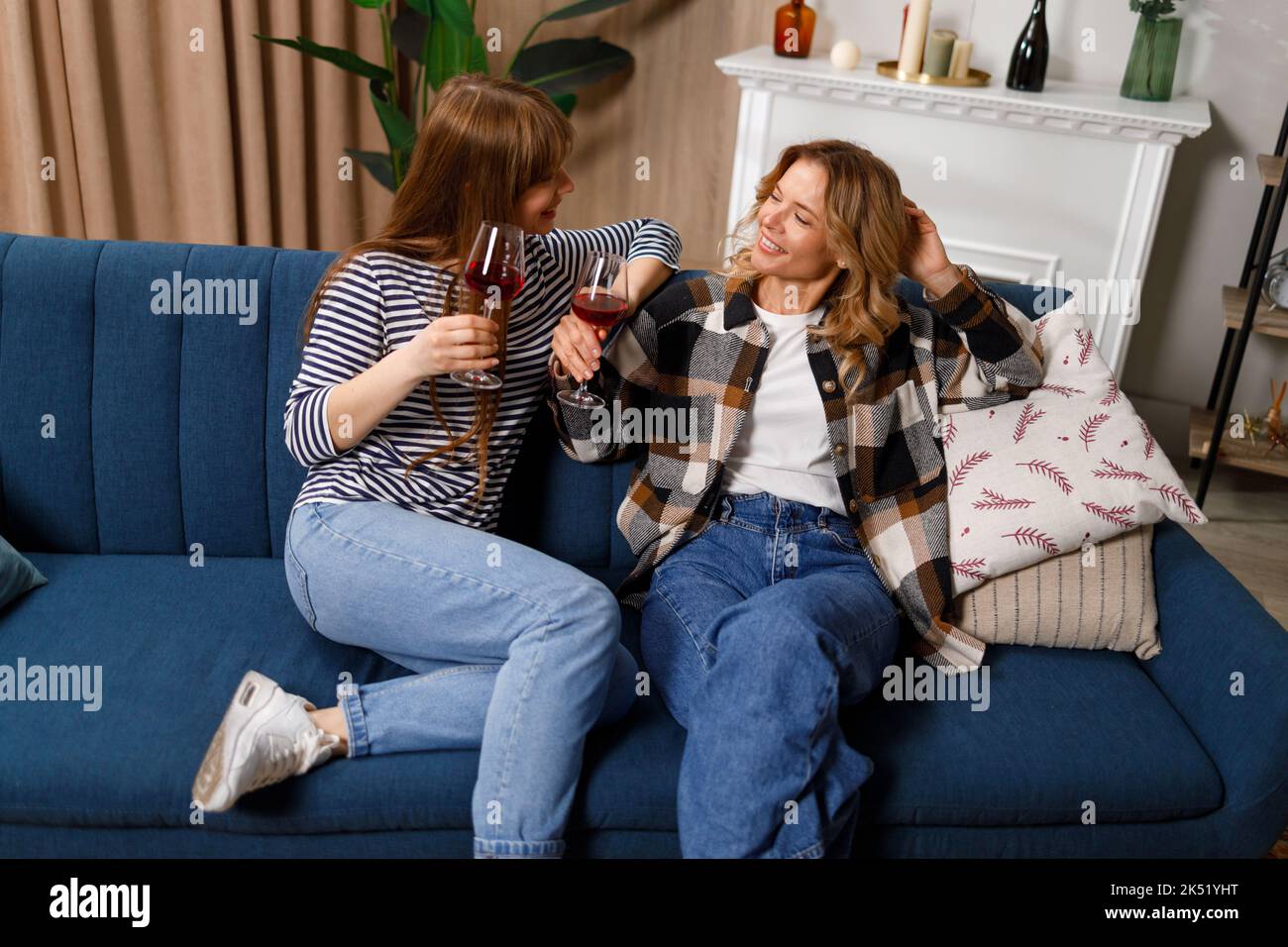 Two women of different ages have fun and friendly gossip and drink wine ...