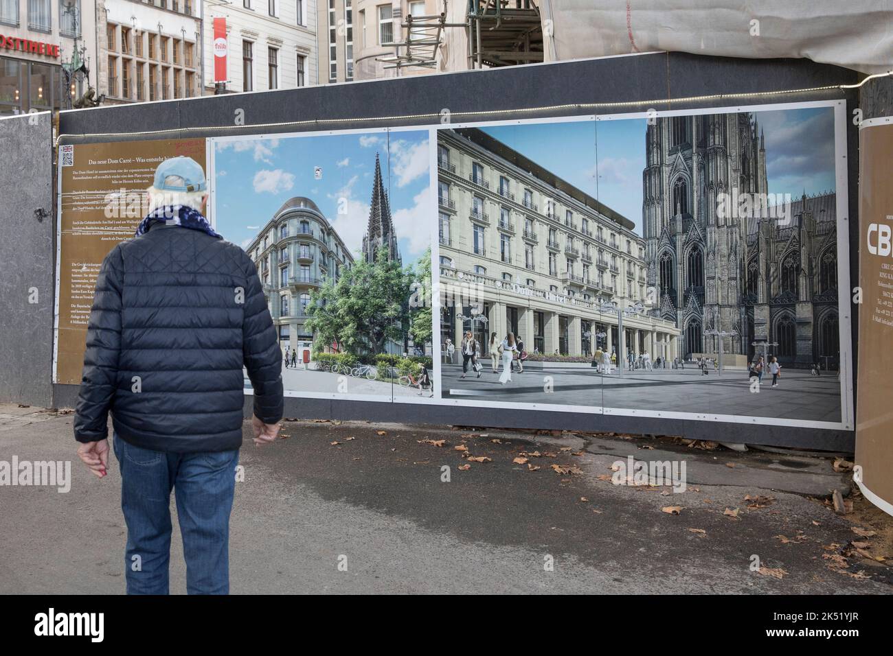 a man pass a construction fence with photos of the future state at the ...