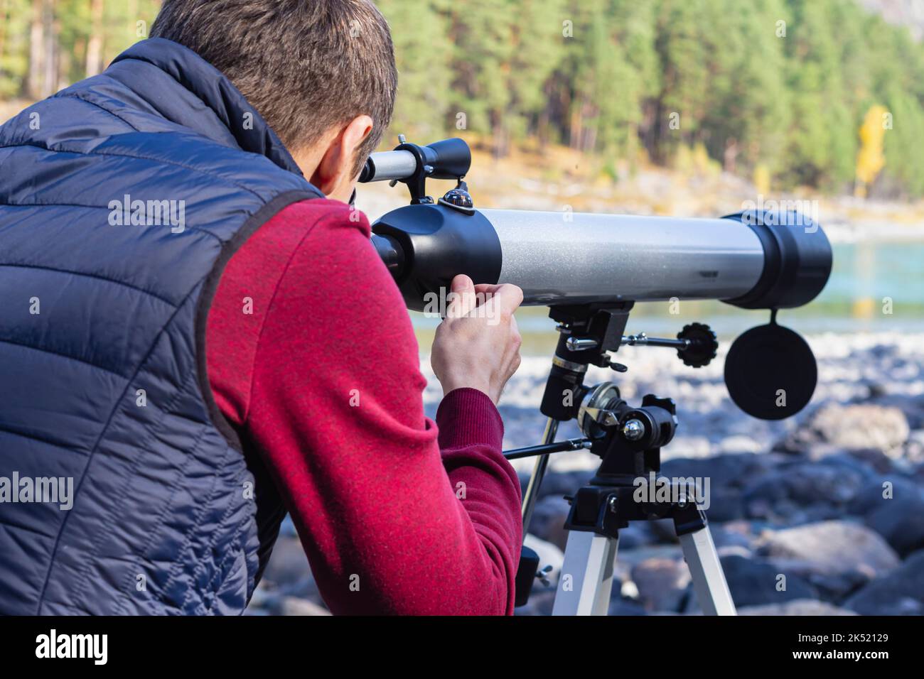 Tourist looking through telescope, View from back, valley of mountain ...