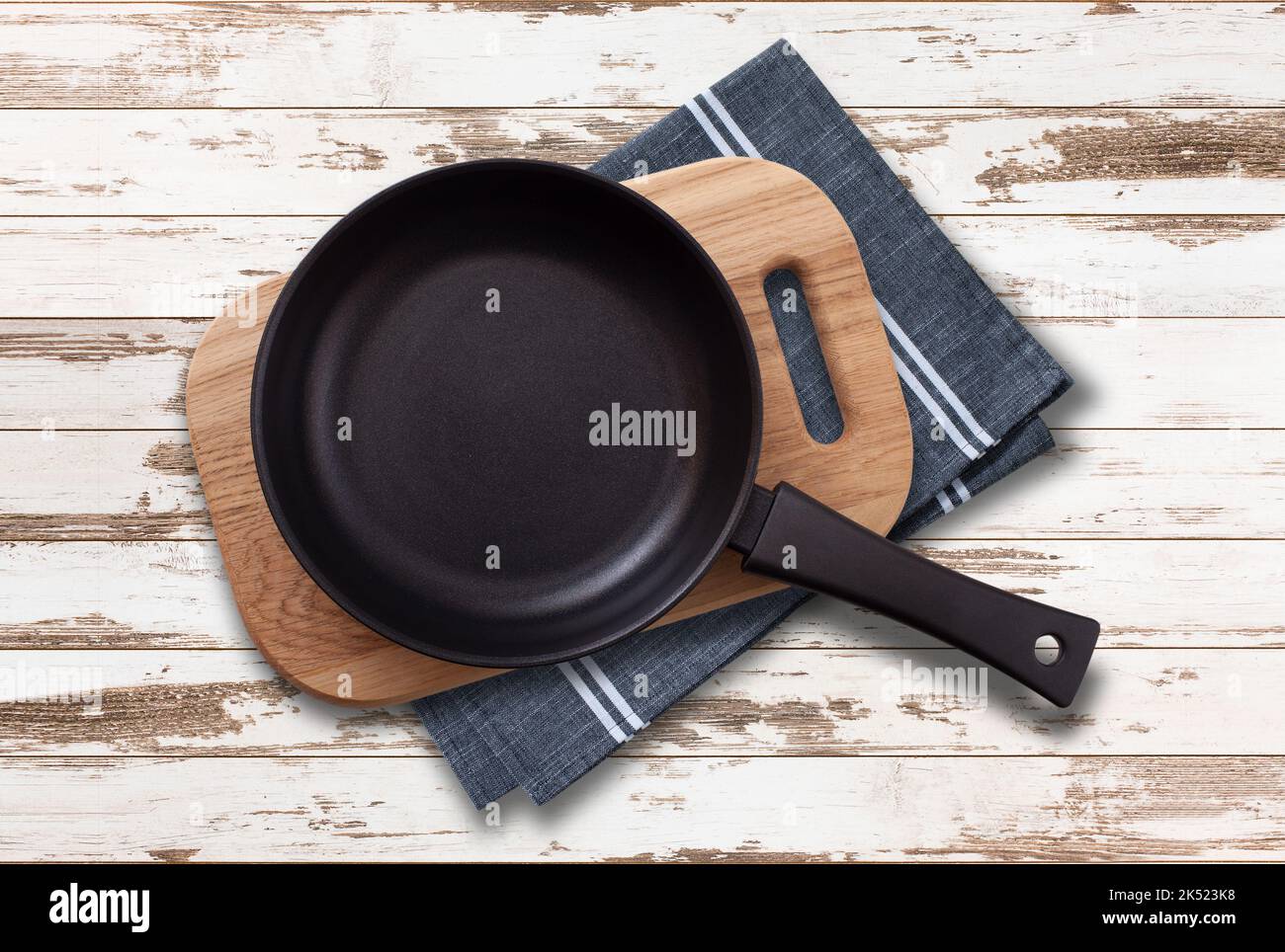Empty fry pan and board with napkin on wooden table. Top view mock up ...