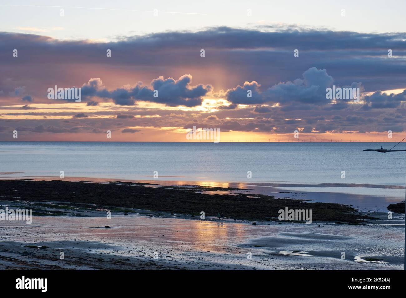 Sunrise over Douglas Bay, Isle of Man. A silhouette of walkers is ...