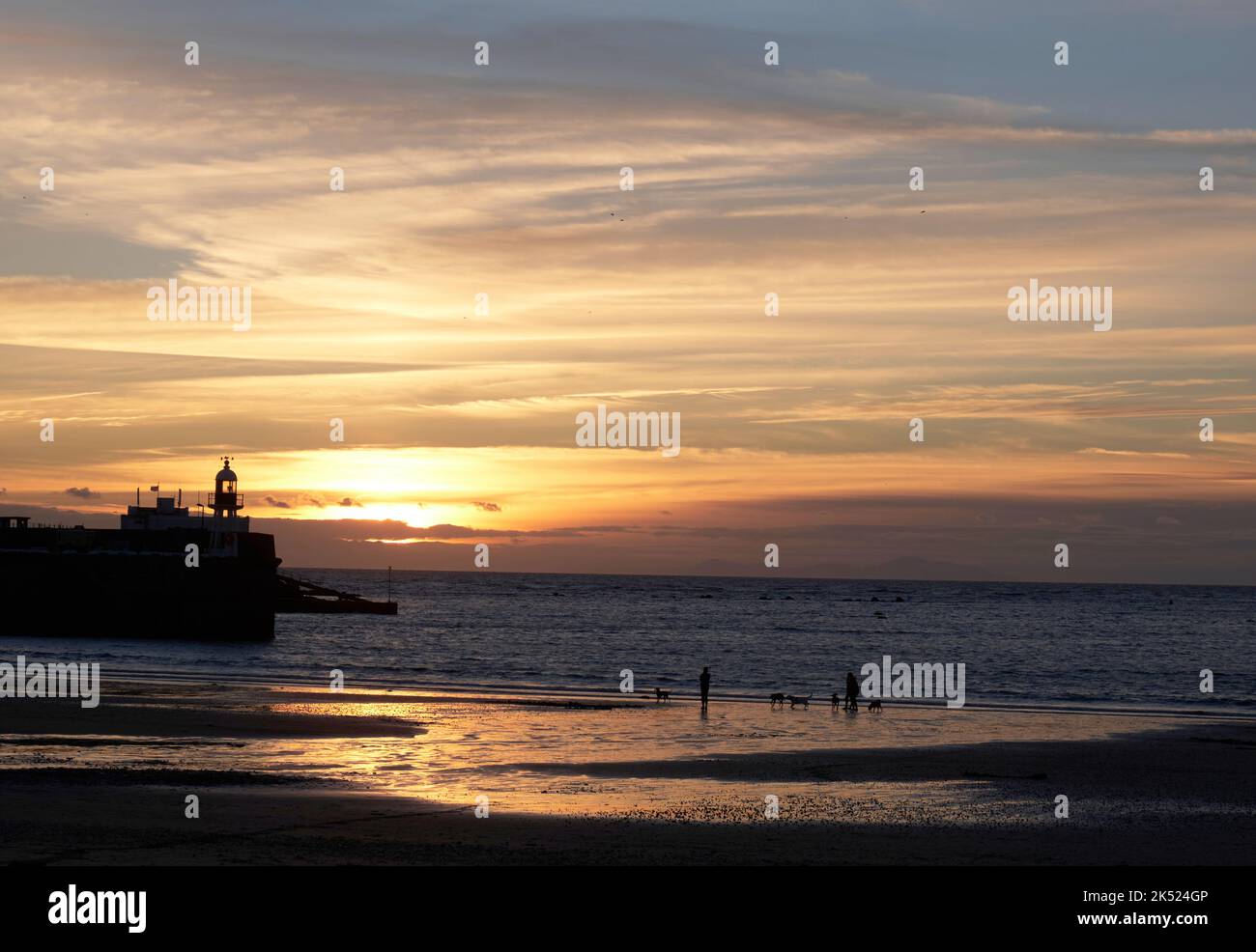 Sunset on Port Erin beach, Isle of Man. The watch tower and two figures ...