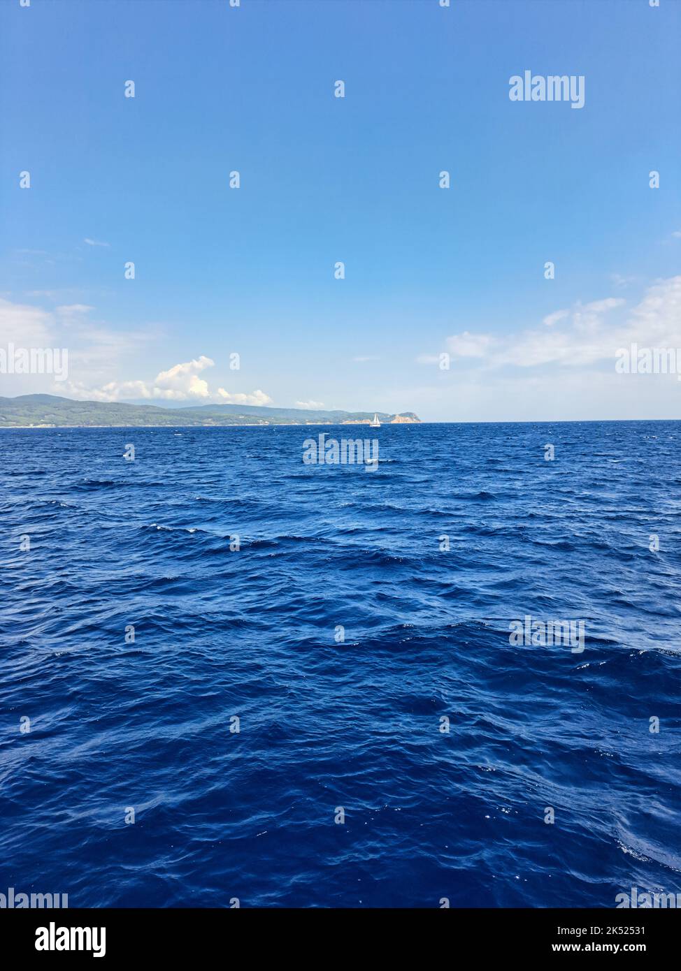 A vertical shot deep blue ocean water with a beautiful landscape in the ...