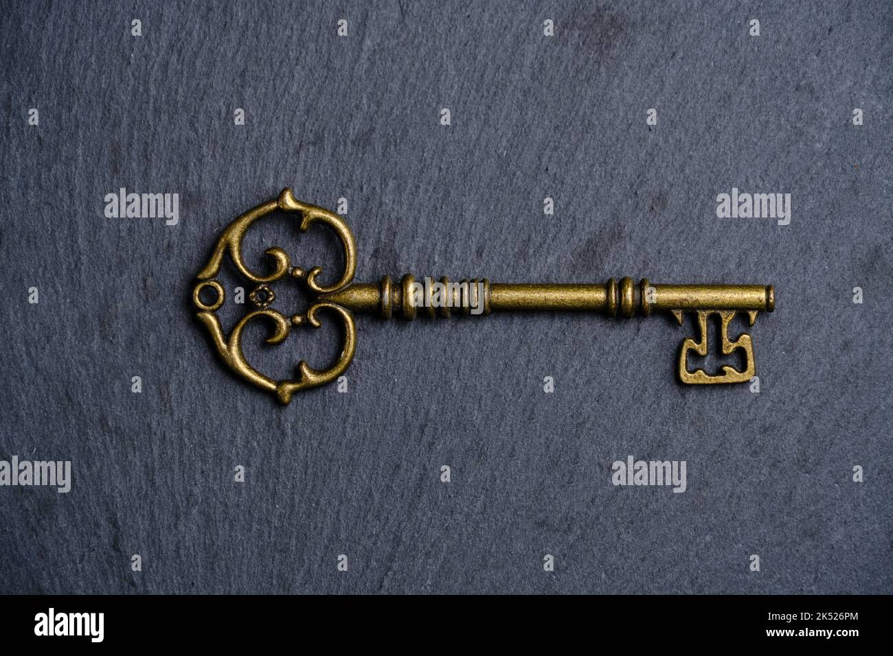 Old vintage key dark slate stone background Stock Photo - Alamy