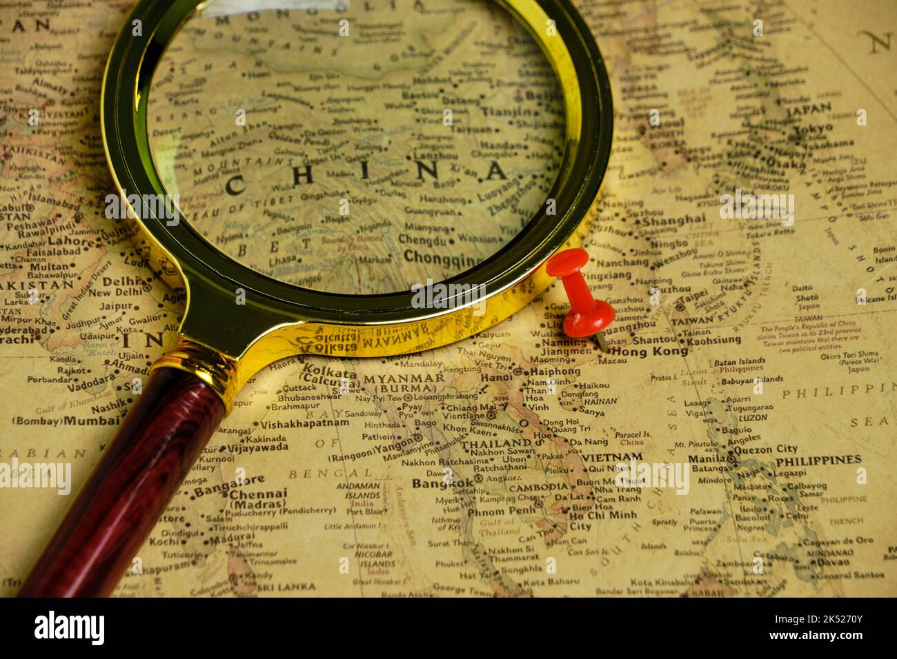 Magnifying glass lying on map next to China and Hong Kong and button ...