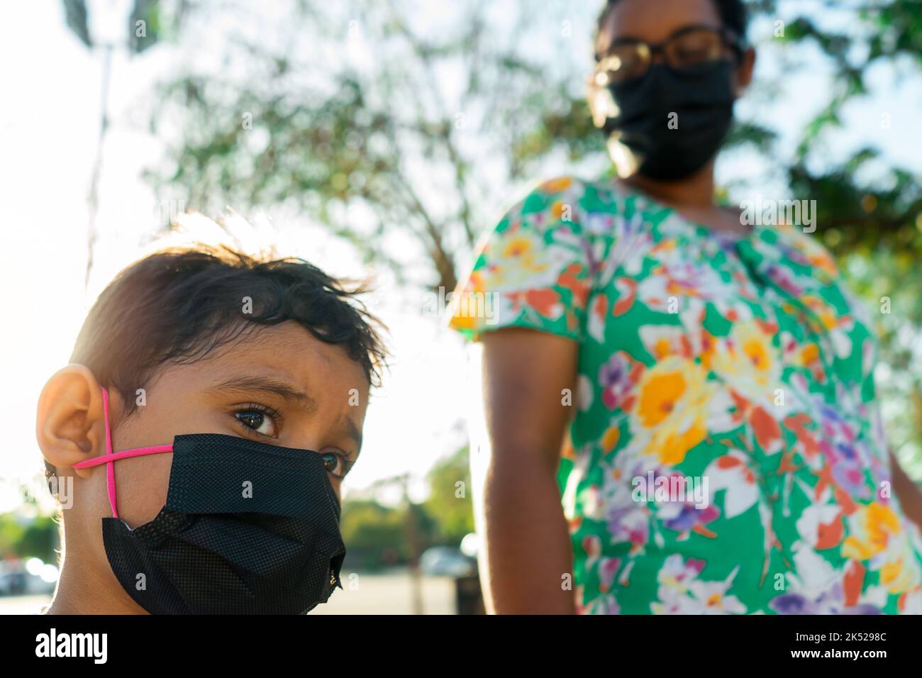 Contrapicado photo Latin mother and son with masks walking outdoors in ...